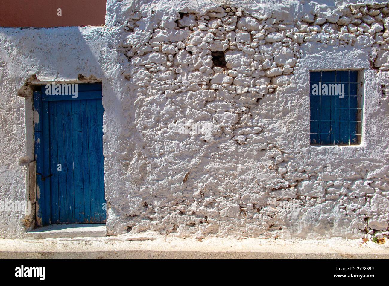 A blue door and shuttered window against a white wall Stock Photo - Alamy