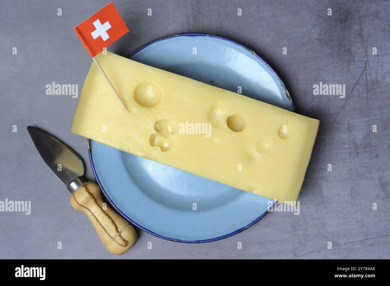 A piece of Swiss Emmental cheese on a plate and the Swiss flag Stock ...