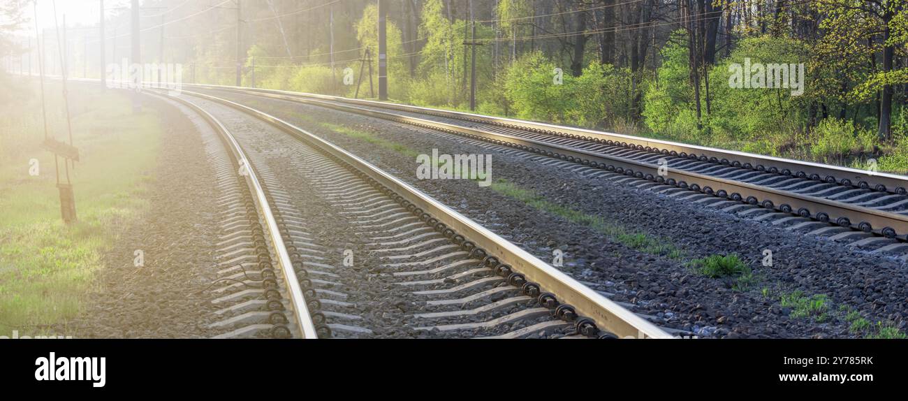 Railway tracks through the forest in the direction of sunrise. Shine of ...