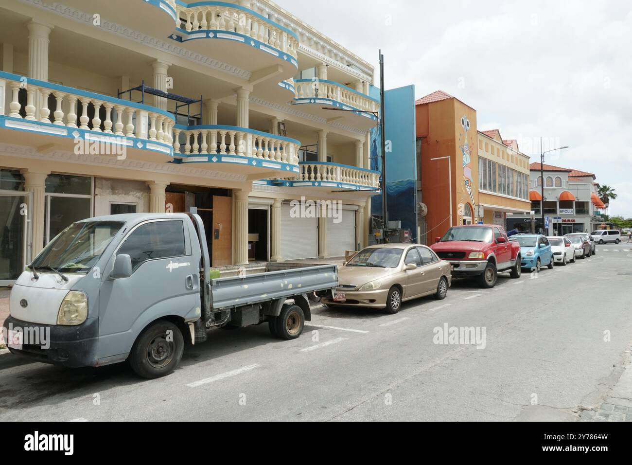 Main road with old buildings in colonial style, palm trees and parked ...