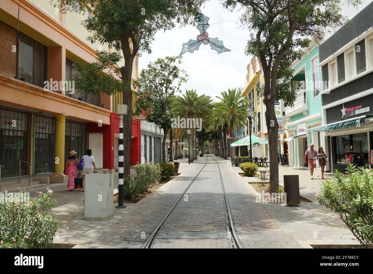 Narrow street with walking people and rails for city tram and colorful ...