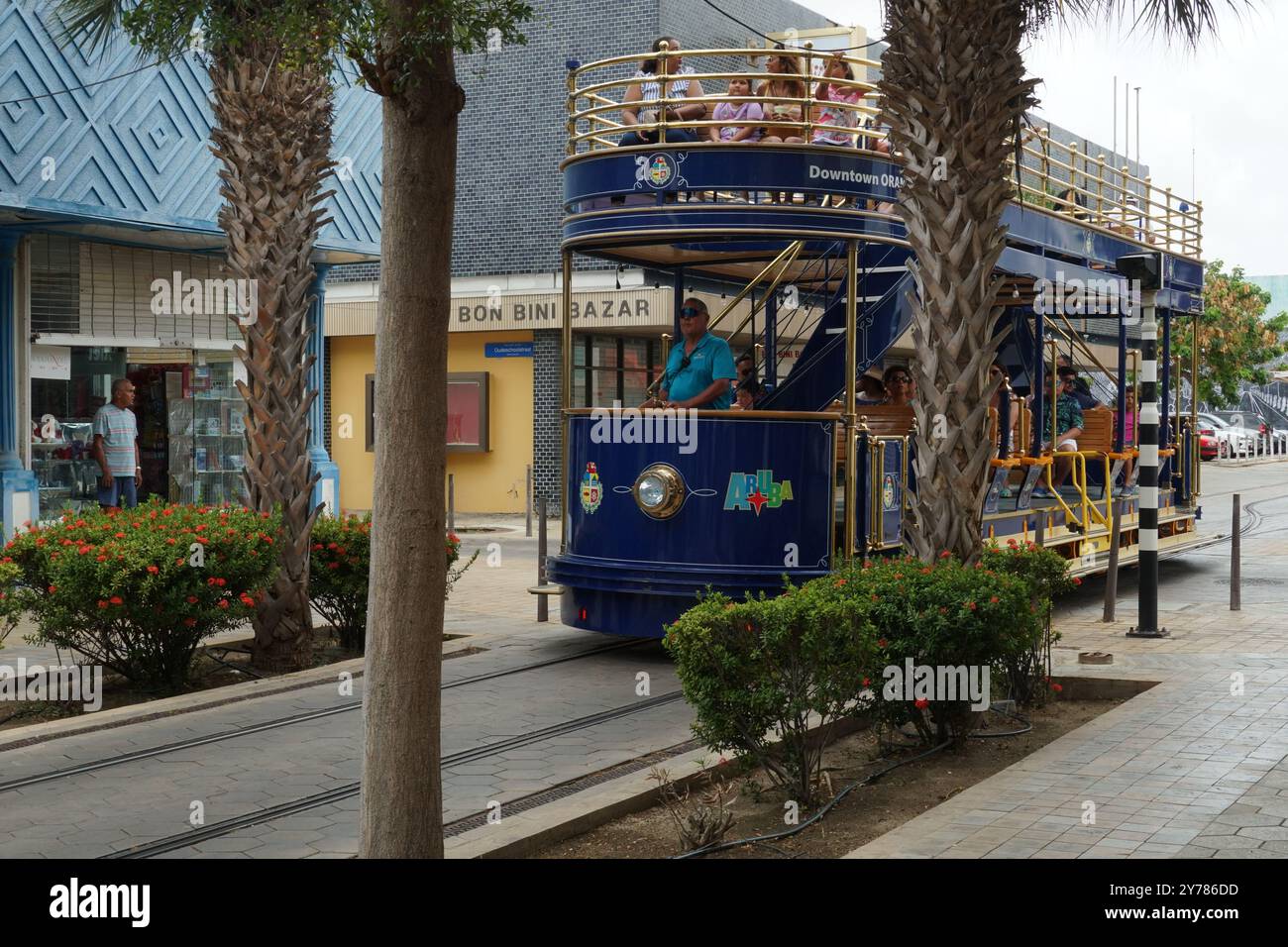 Downtown trolley full of tourist passing narrow street with colorful ...