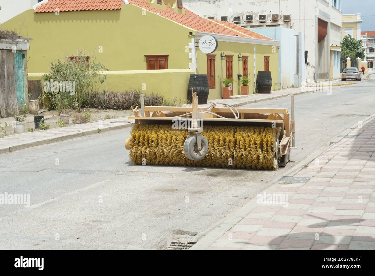 Yellow broom for street sweeper in downtown district with colorful old ...