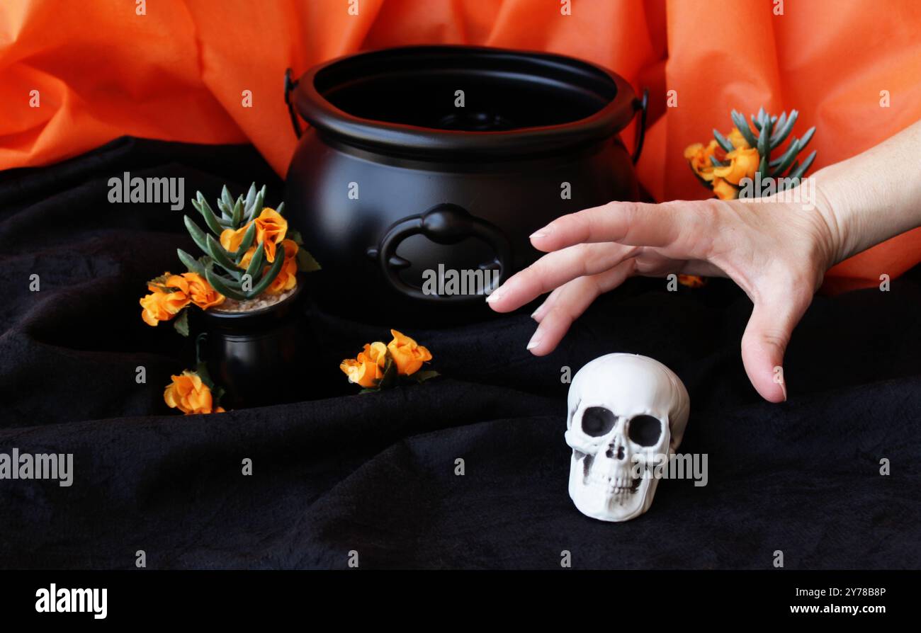 Witch hand reaching for a Halloween skull on a table set with black ...