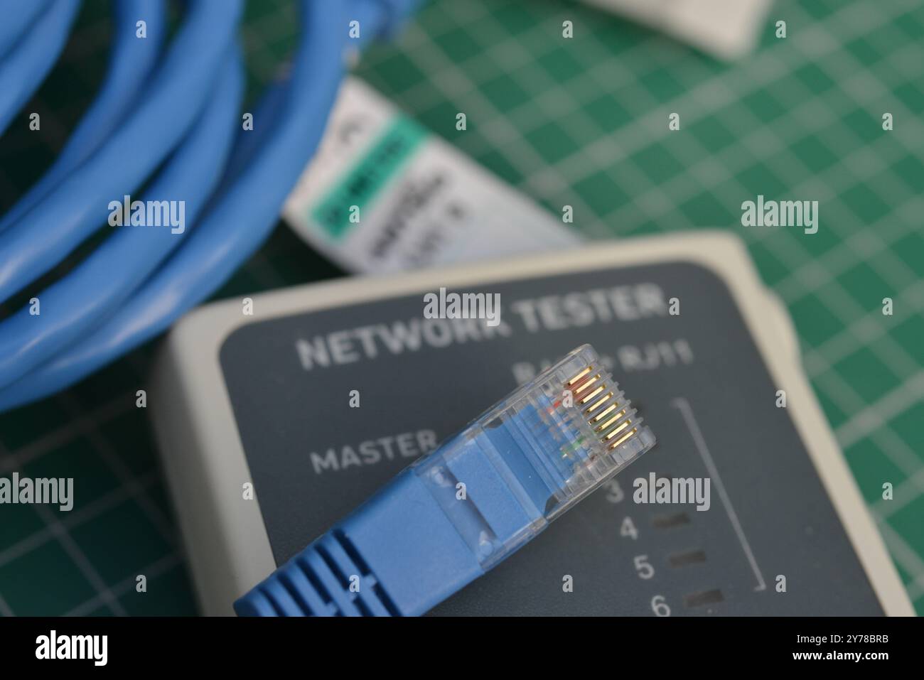 An Ethernet plug together with a cable tester and spool of blue cable ...