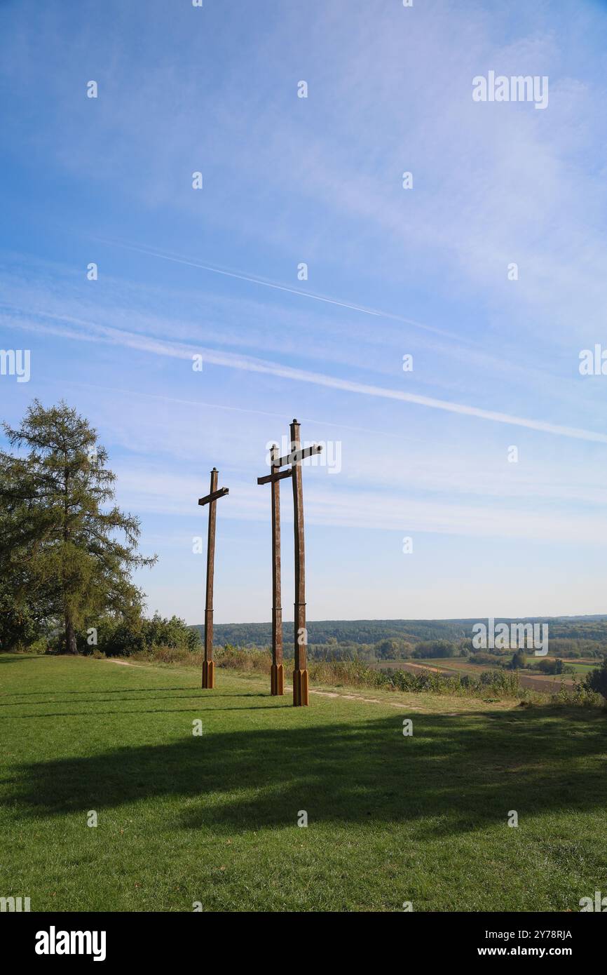 A peaceful scene with three wooden crosses on a grassy hilltop, set ...