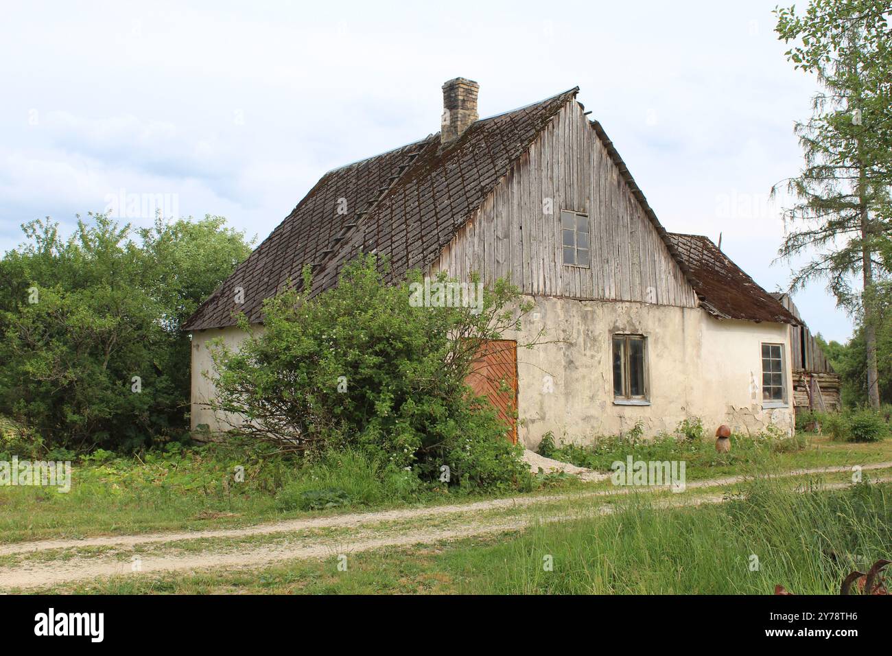Traditional Latvian farmhouse with a gravel road in front of it in the ...