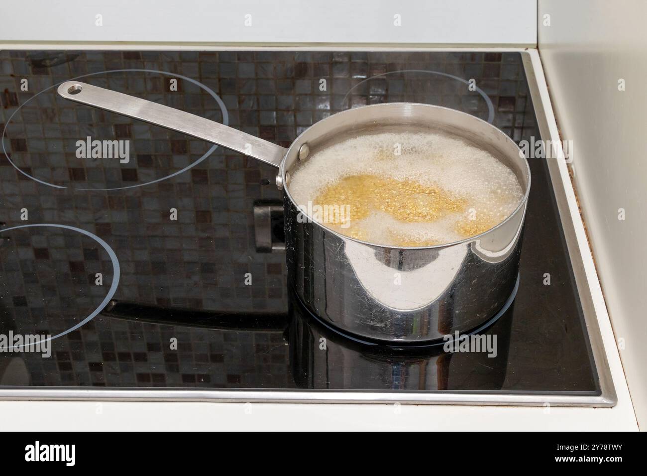 Pasta cooking inside metal pot on glass stove panel inside kitchen ...