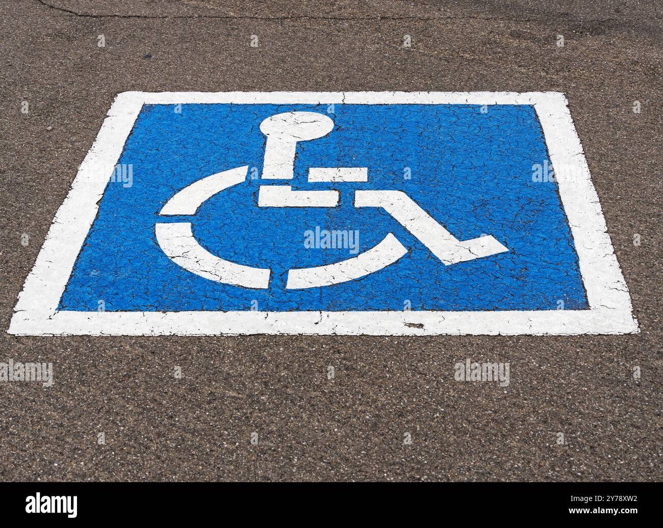 white and blue wheelchair handicapped parking stencil on old asphalt ...