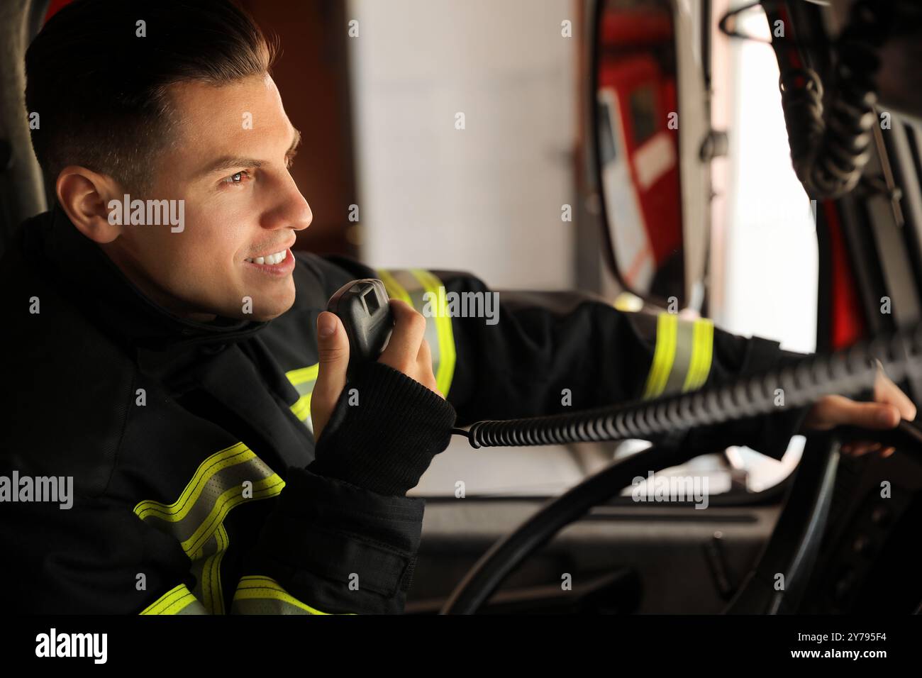 Firefighter using radio set while driving fire truck Stock Photo - Alamy
