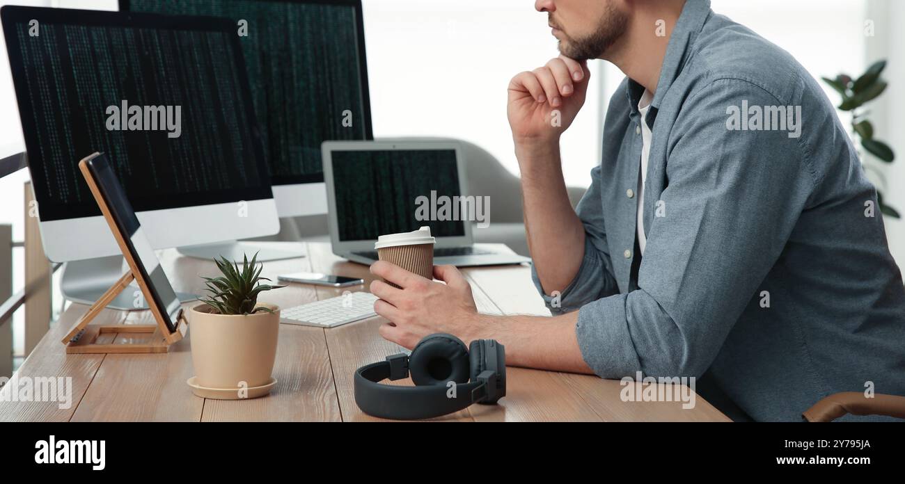 Programmer with coffee working at desk in office, closeup. Banner ...