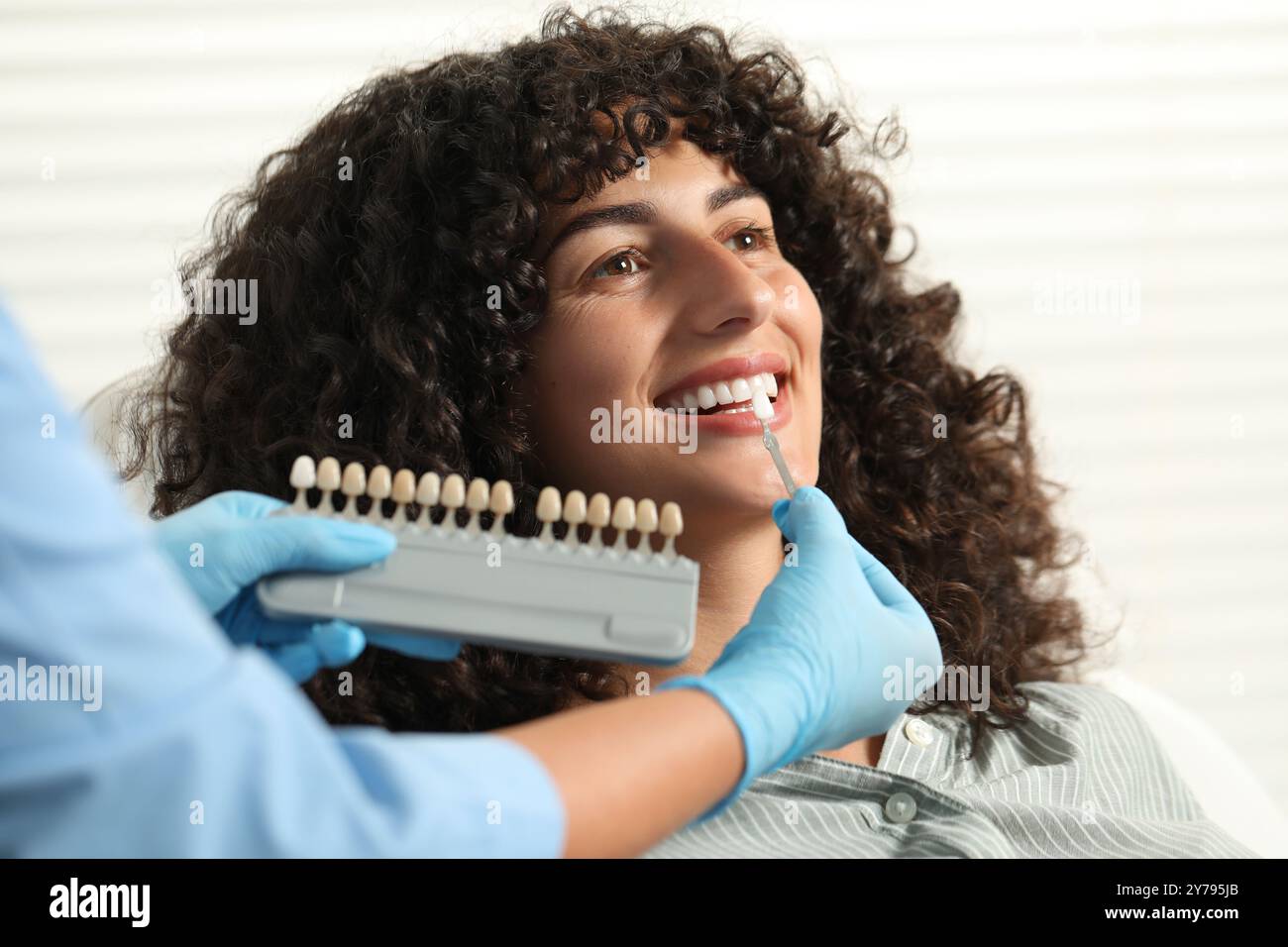 Doctor checking young woman's teeth color in clinic, closeup. Dental ...