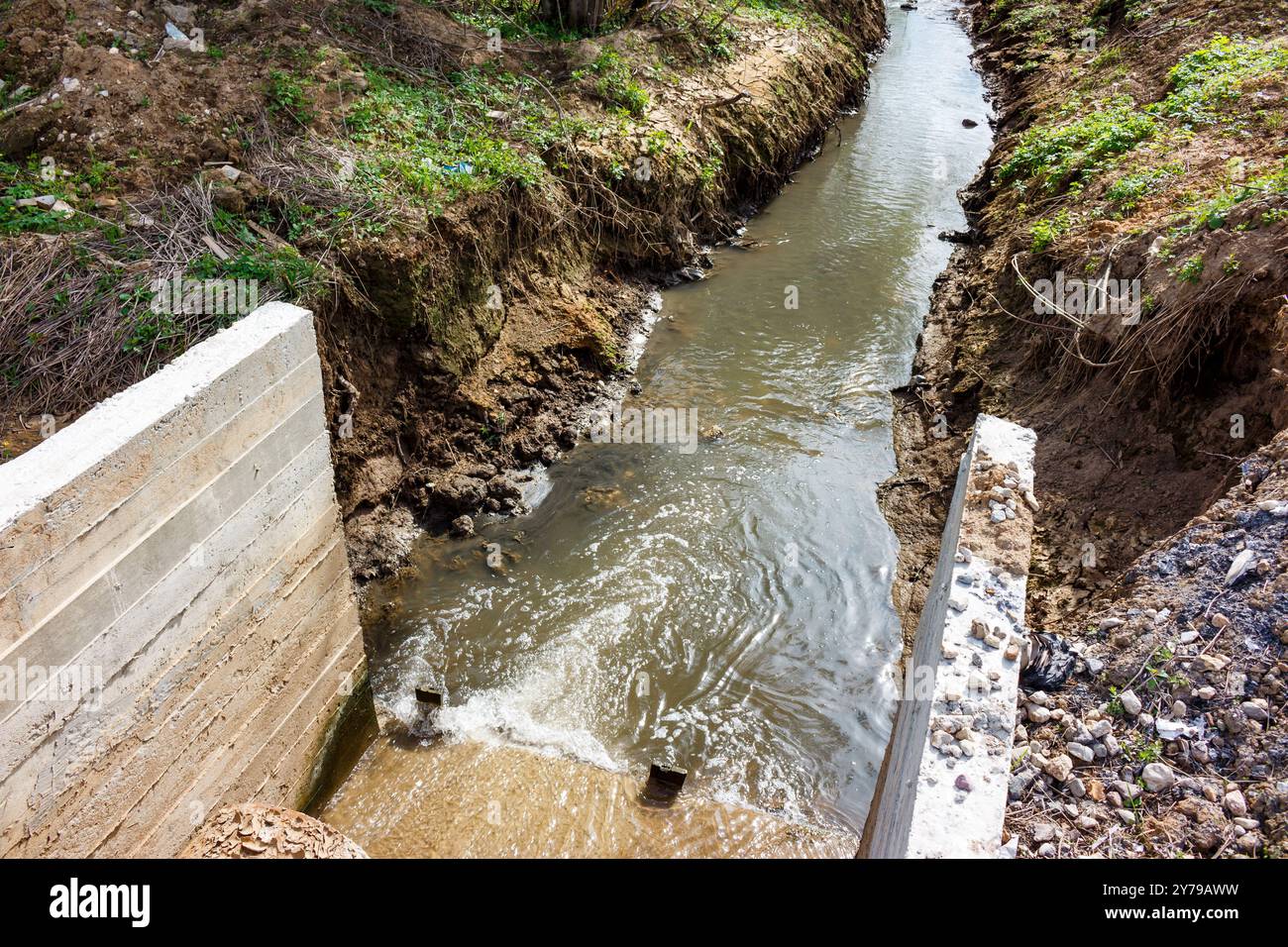 Channel with water flowing out of a tunnel under a road Stock Photo - Alamy