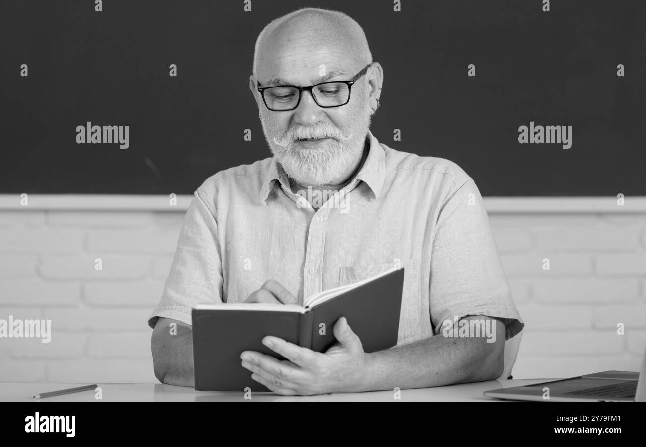 Senior teacher teaching in the classroom on chalkboard. Teacher at ...