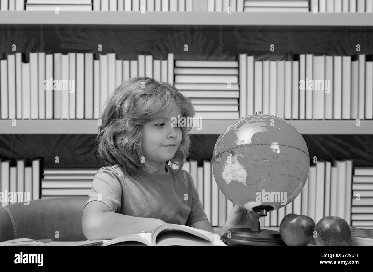 School boy looking at globe in library, geography lesson. School child ...