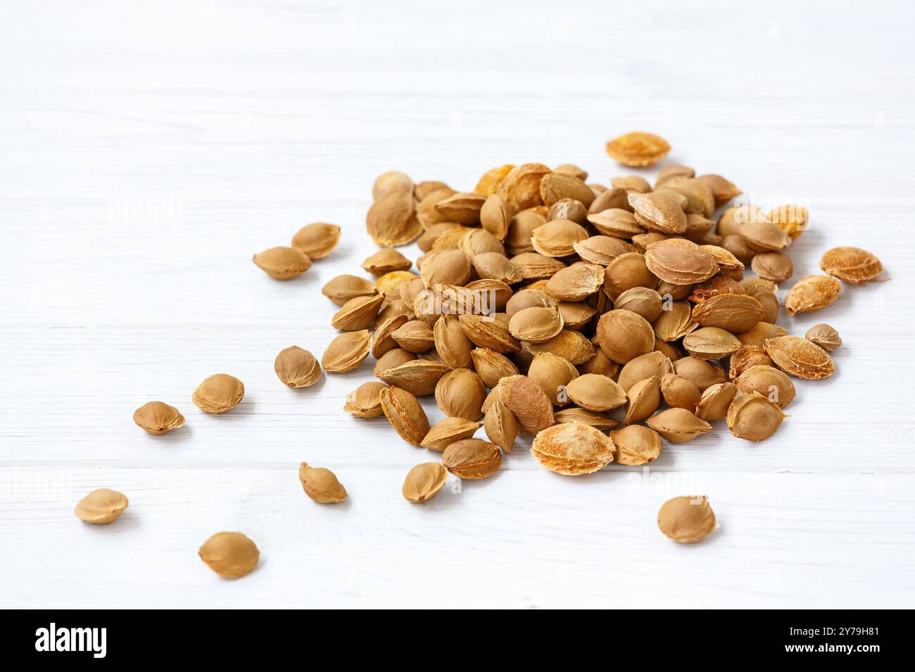 A pile of apricot pits on a light background. View from above. Vitamin ...