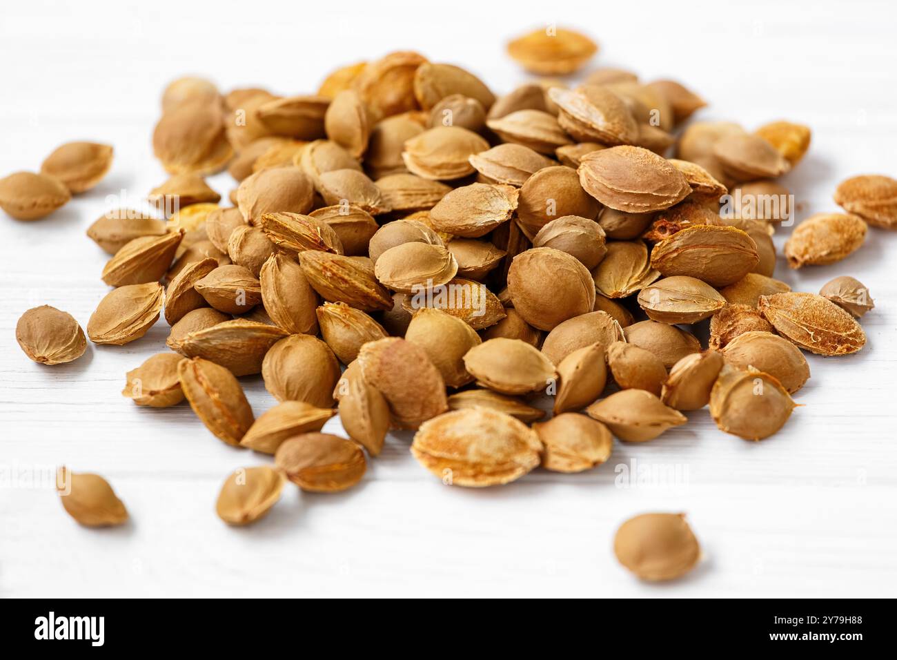 A pile of apricot pits on a light background. View from above. Vitamin ...