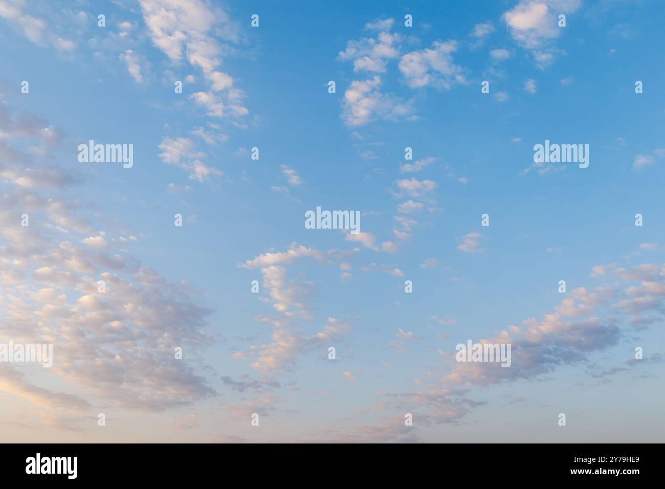 A clear blue sky with light, scattered small clouds at dawn stretching ...