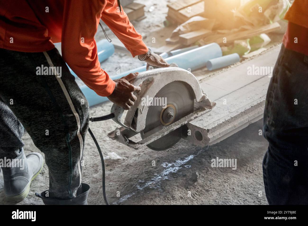 A builder using a circular saw to cut a large concrete piece Stock ...