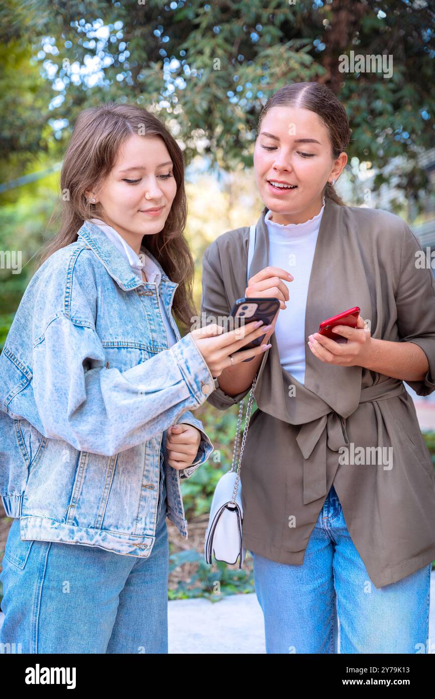 Vertical portrait two happy teenage friends using smartphone app ...