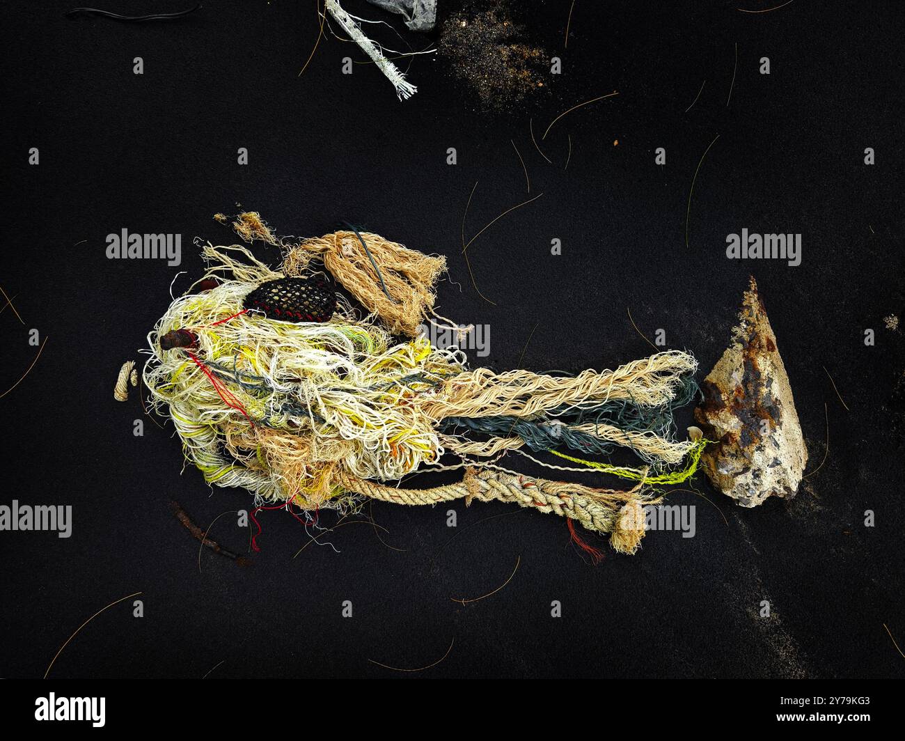 There is a pile of tightly wound rope and colorful yarn on a black ...