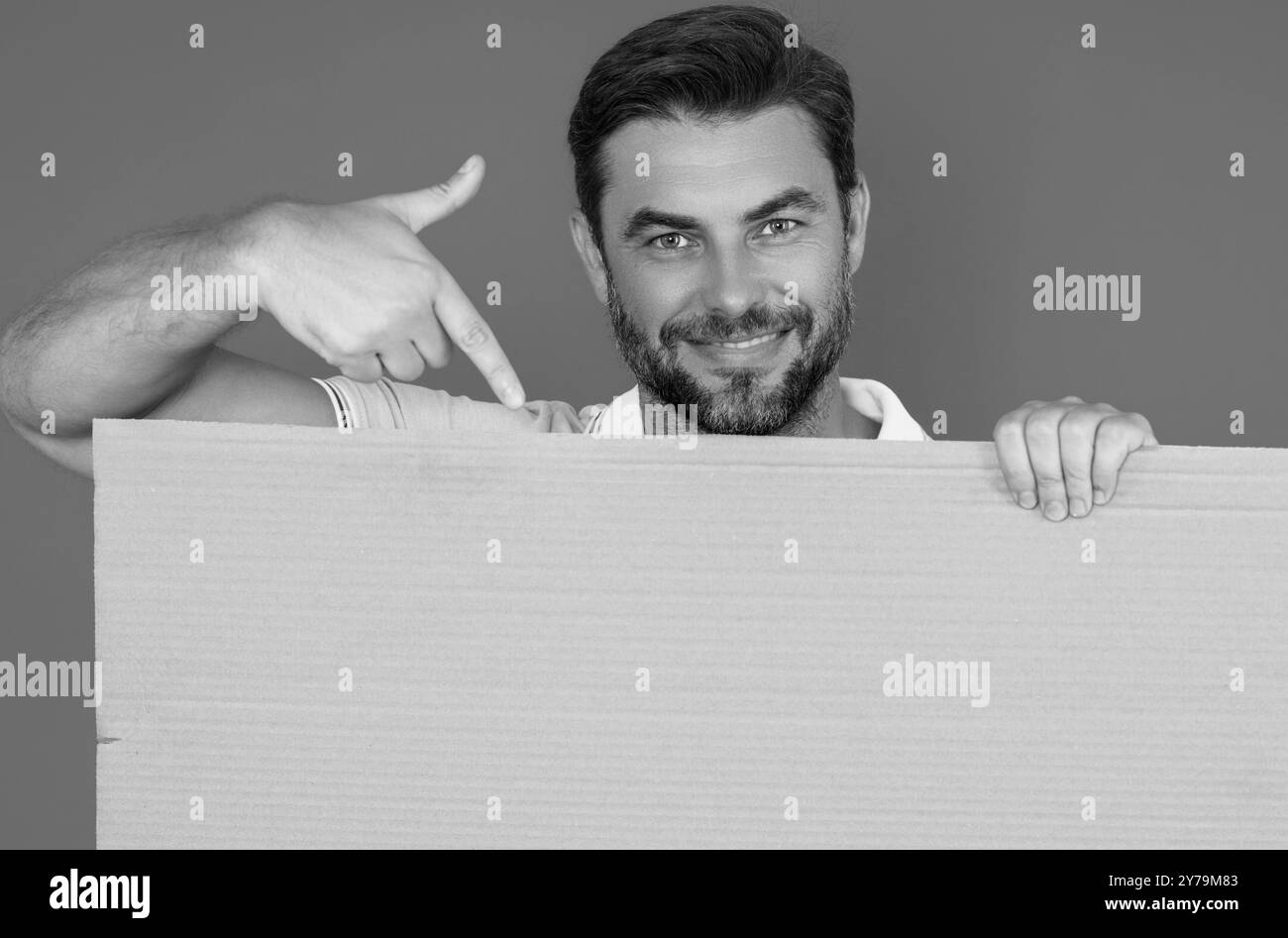 Man showing promo holding pointing finger on blank board on studio ...