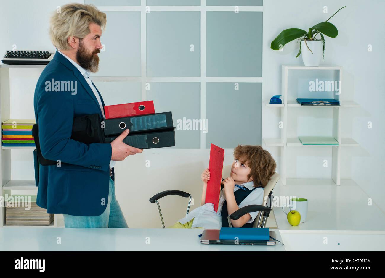 Little boy playing to be boss on a business desk in office. Colleagues ...