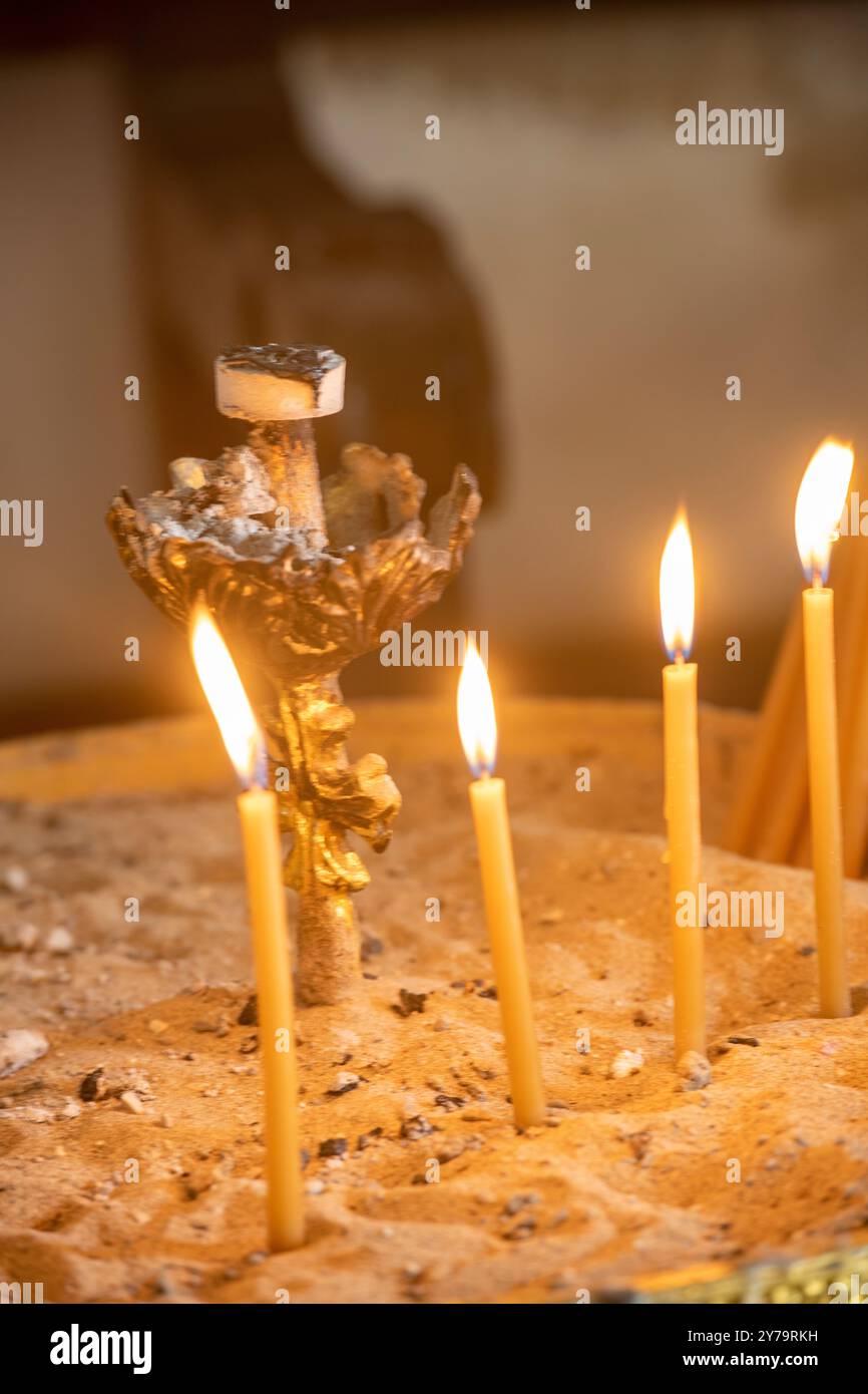 prayer or votive candle and ornamental altar candlestick in a church ...