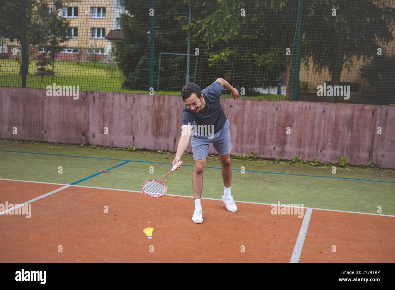 Badminton player stretches to retrieve a low shuttlecock during an ...