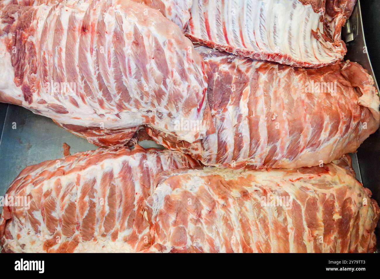 Rack of ribs is displayed in a metal tray. The ribs are white and red ...