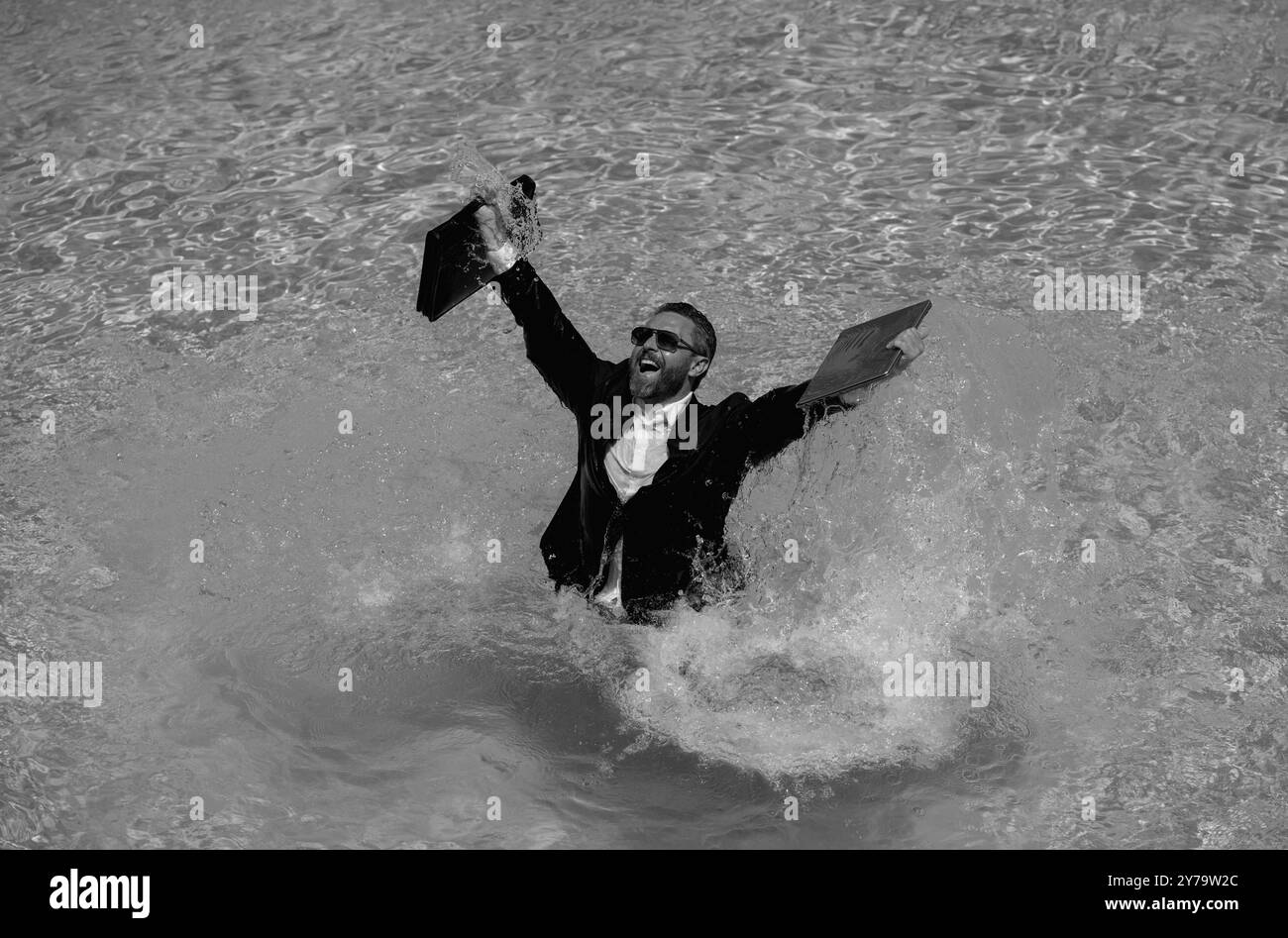 Business man in suit with laptop excited jumping in swimming pool ...