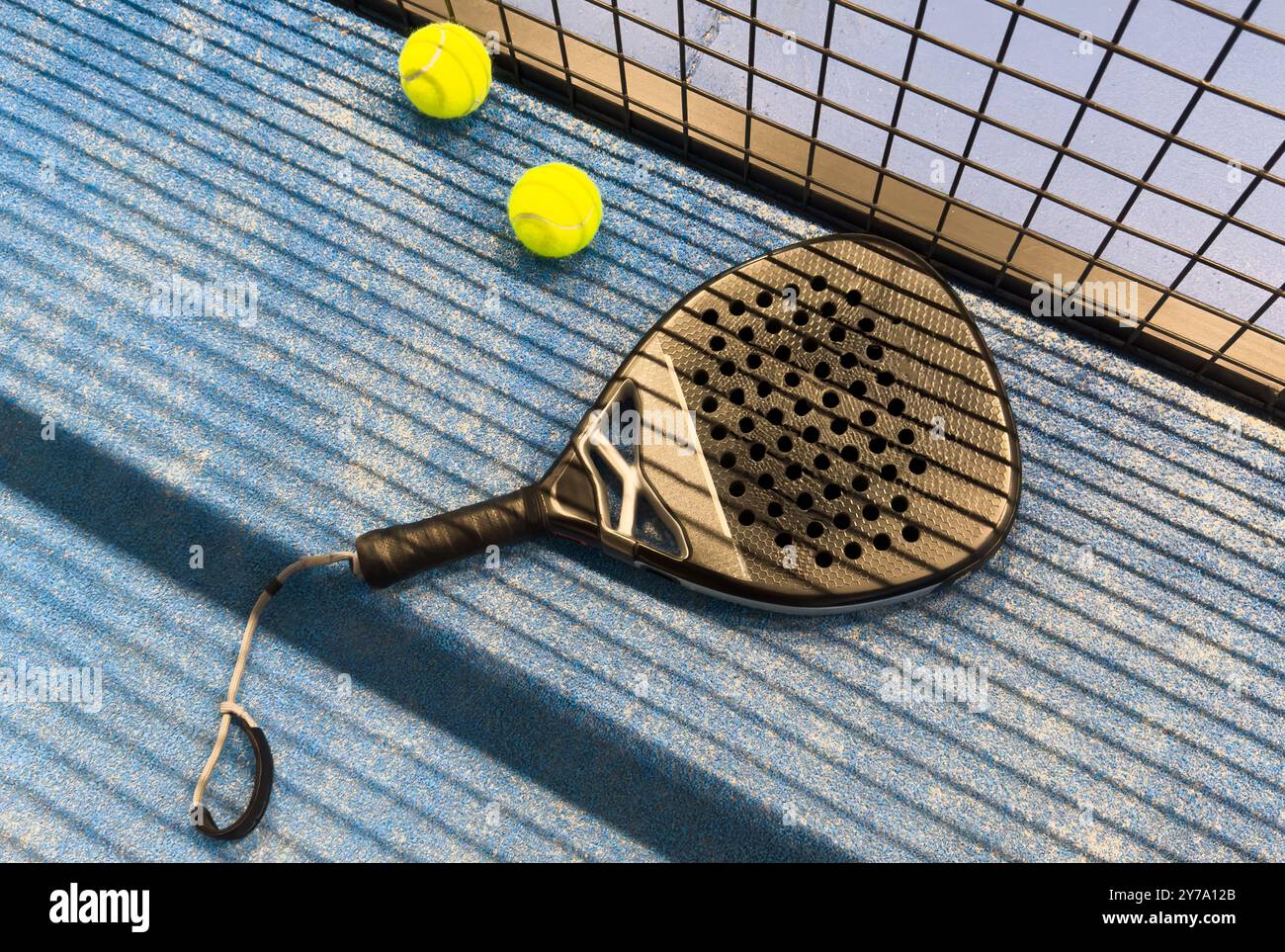 Padel racket and yellow ball behind net on a green court grass turf ...