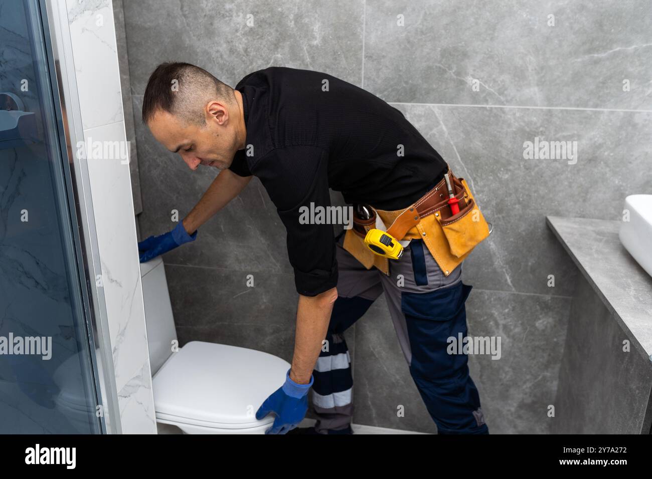 Professional plumber in uniform fixing toilet tank indoors Stock Photo ...