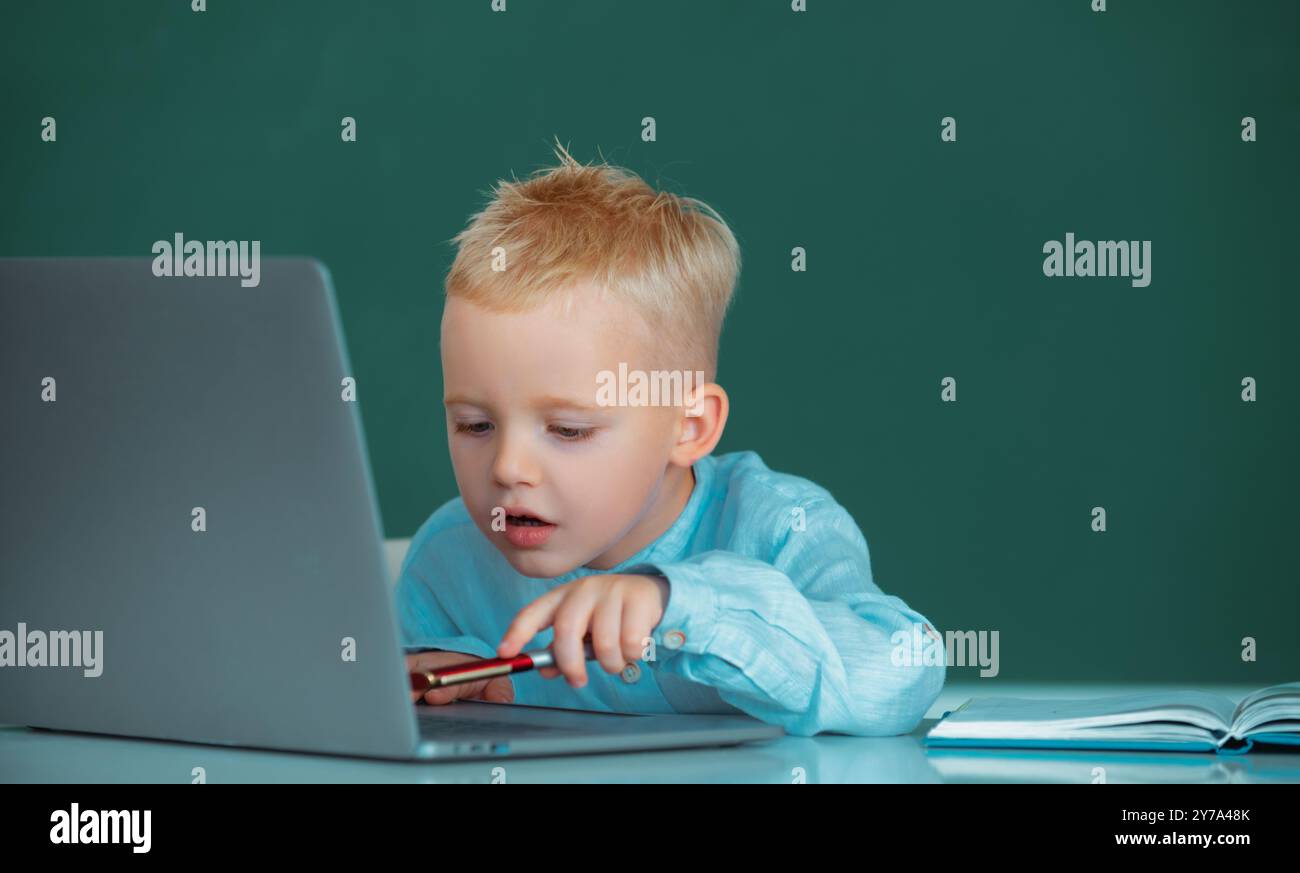 School child using digital pc laptop in class. Portrait of funny pupil ...