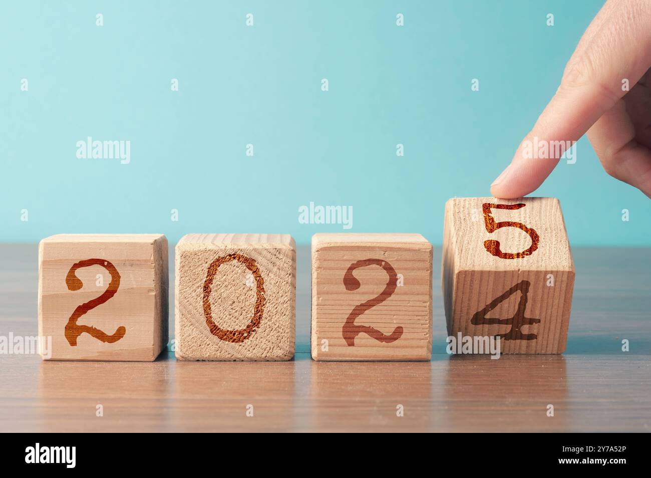 A businessman turns a wooden cube from 2024 to 2025, New Years concept ...