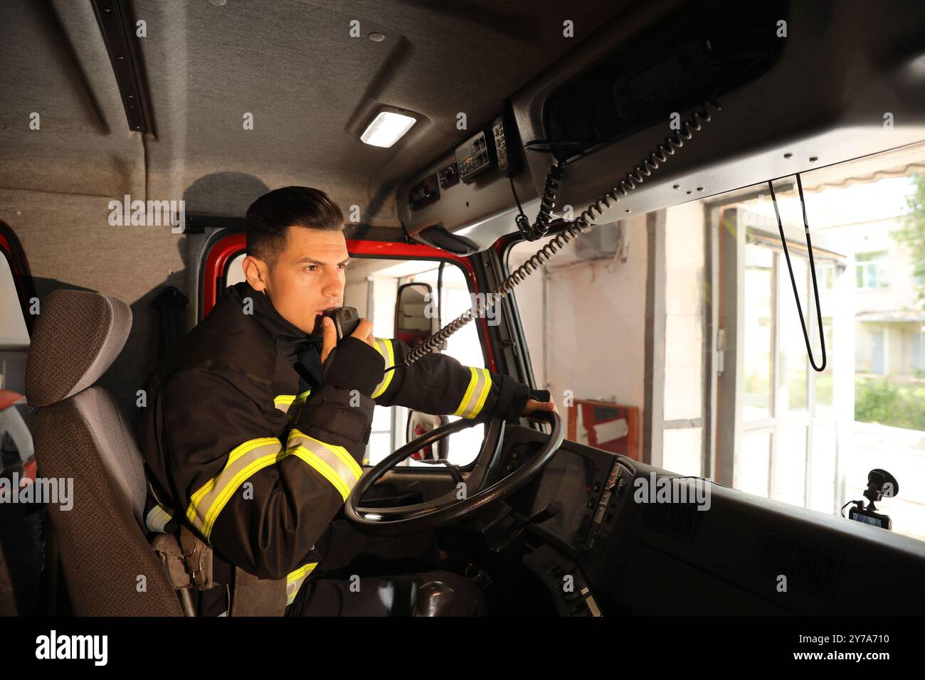 Firefighter using radio set while driving fire truck Stock Photo - Alamy