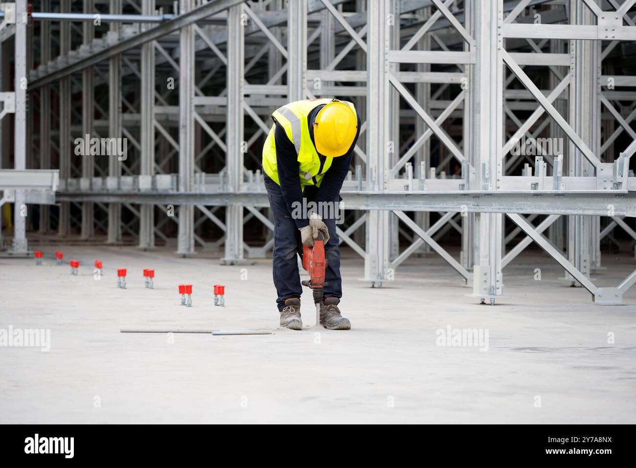 Worker drilling holes for chemical anchors in concrete foundation slab ...