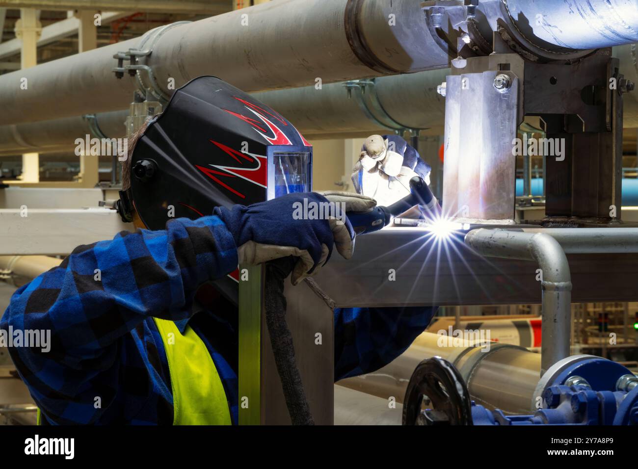 Welder welding steel elements with TIG MIG method indoors in protective ...