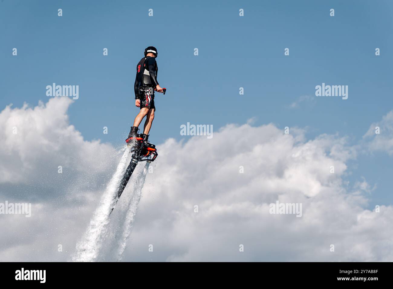 Man wearing a helmet and life jacket is flying using a flyboard ...