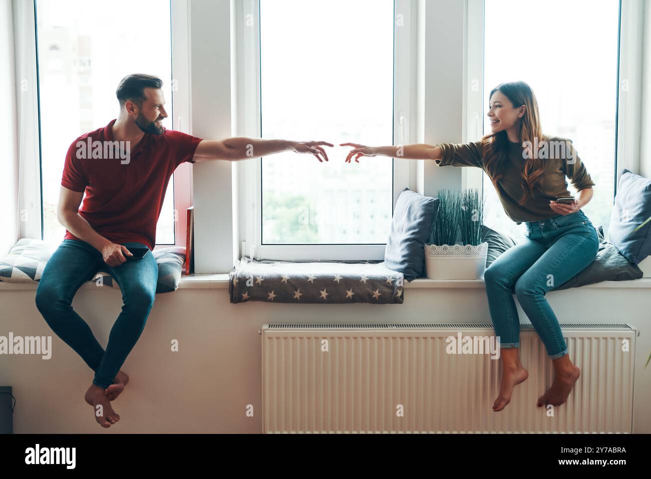 Beautiful young couple in casual clothing reaching each other with ...