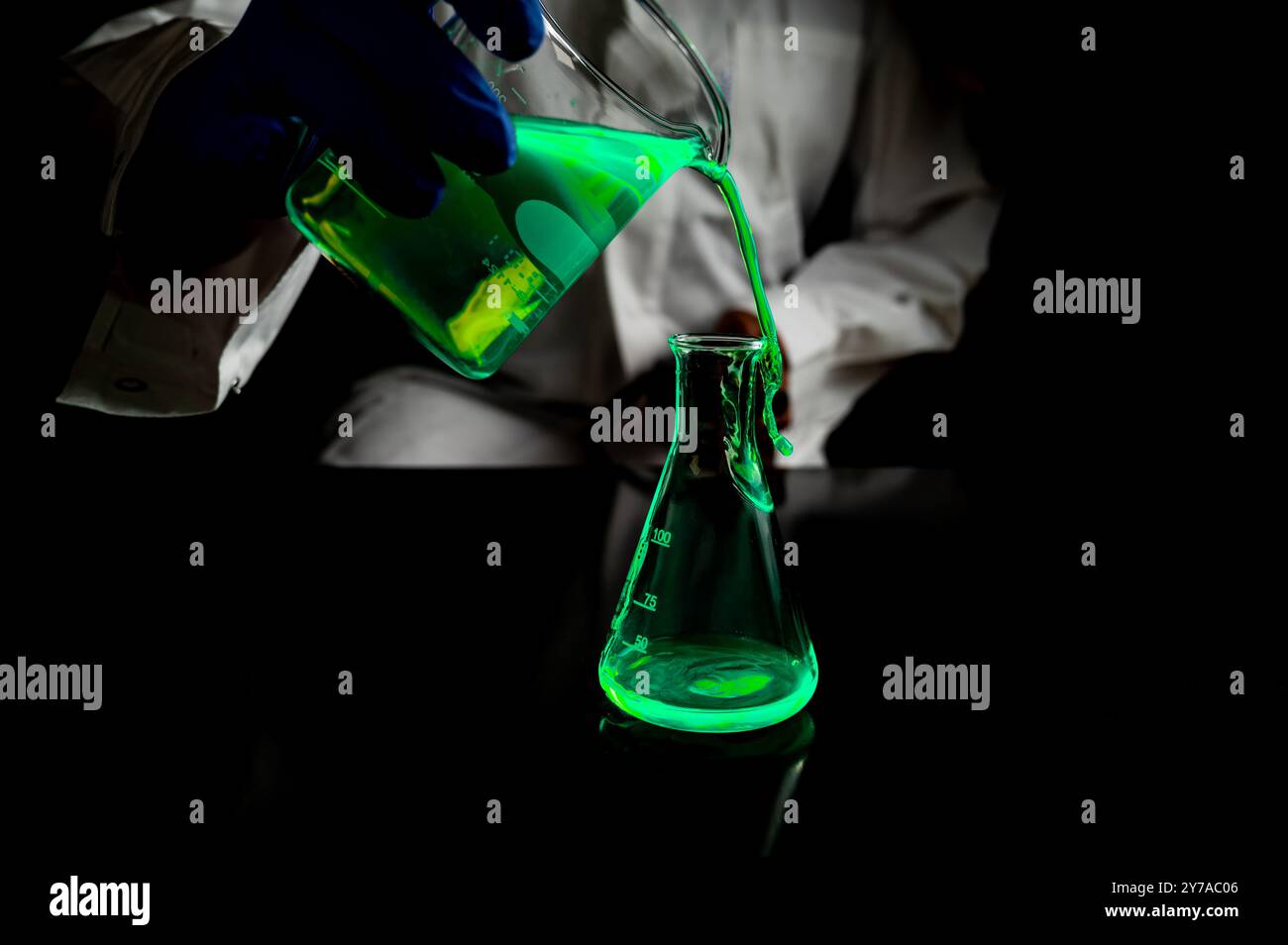 A research scientist experimenting with a green fluorescent solution in ...