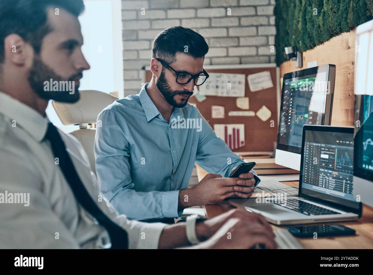 Two handsome young modern men in formalwear working using computers ...