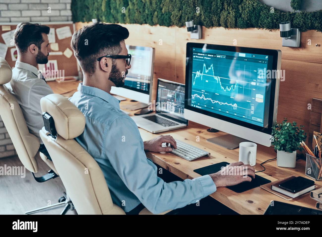 Two young modern men in formalwear working using computers while ...