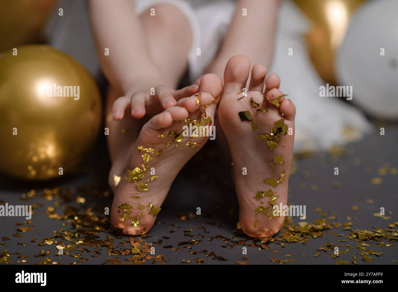 golden confetti on the girl's feet. birthday celebration. the concept ...