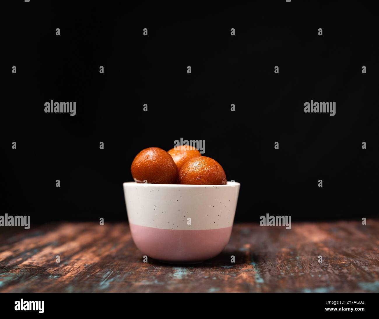 Gulab Jamun served in a bowl with pouring sweet syrup. Gulab Jamun is a ...