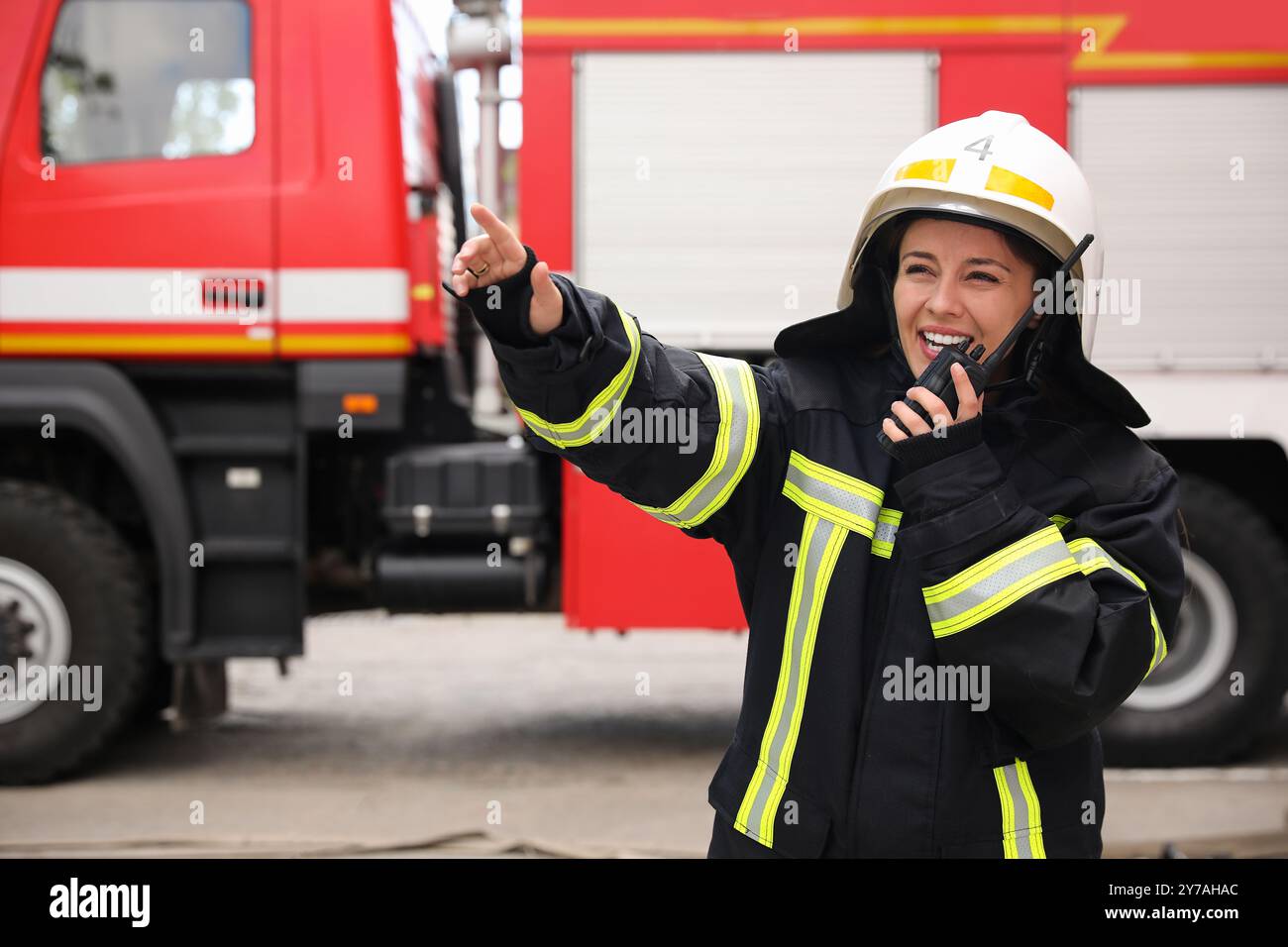 Firefighter in uniform using portable radio set near fire truck ...