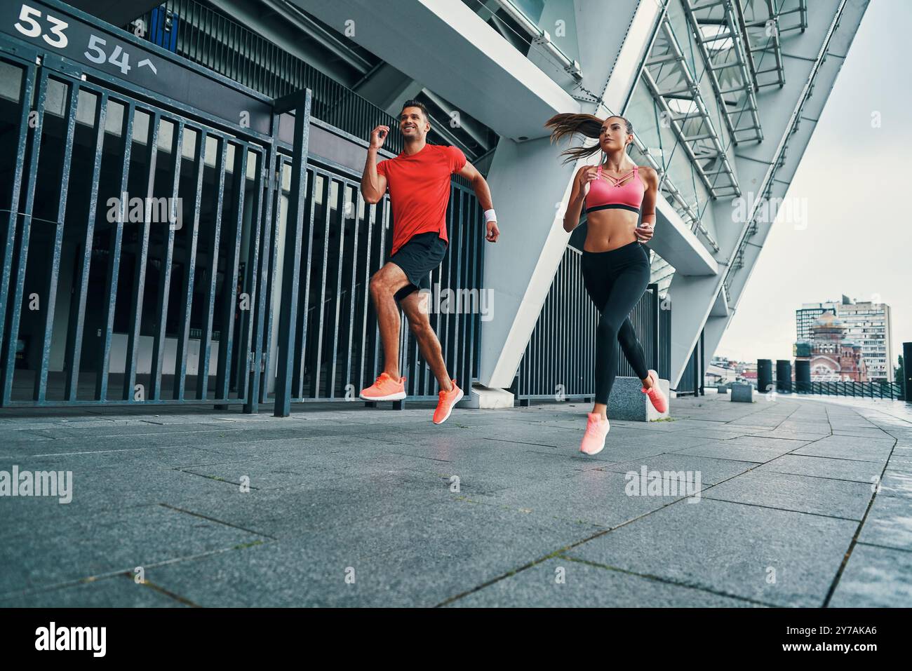 Full length of two young athletes in sports clothing running while ...