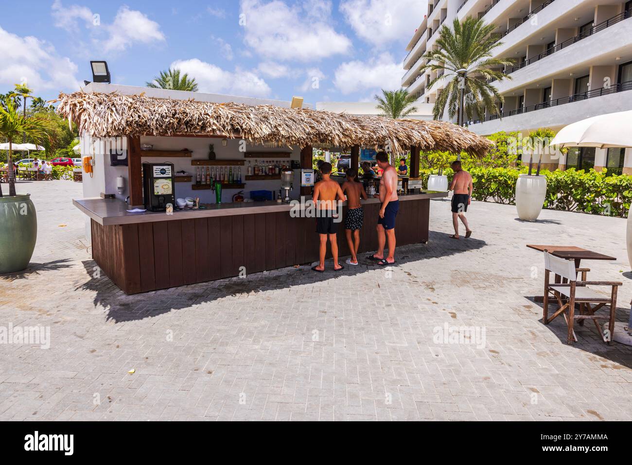 Outdoor beach bar with thatched roof serving drinks to tourists on ...