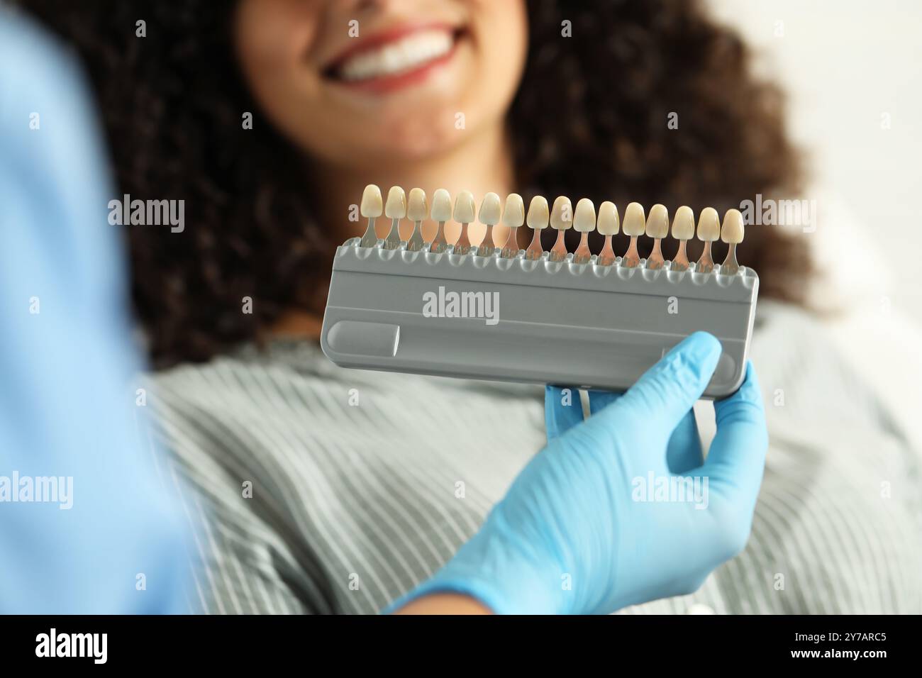 Doctor checking young woman's teeth color in clinic, closeup. Dental ...