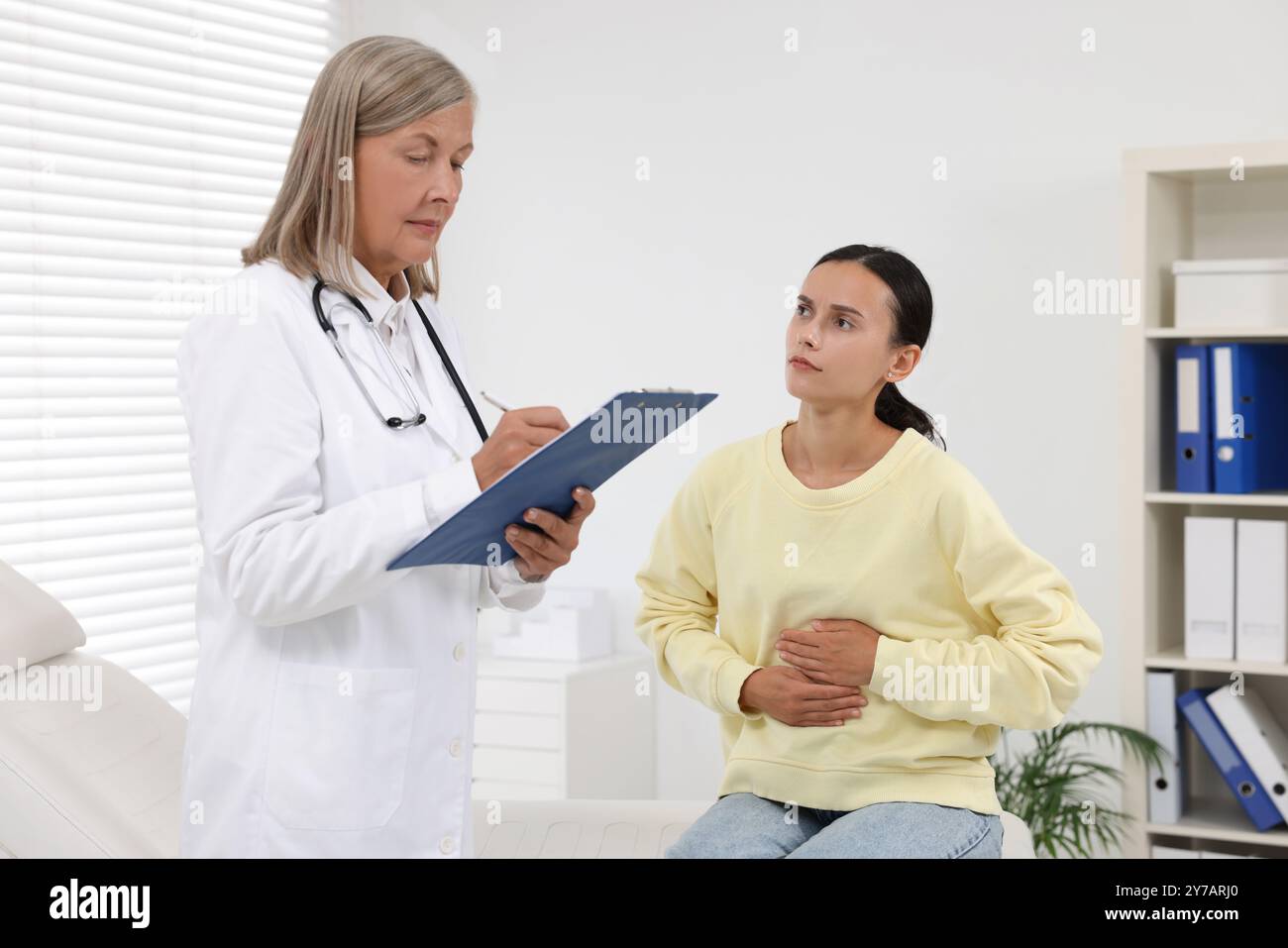 Senior doctor consulting patient with stomach pain in hospital Stock ...